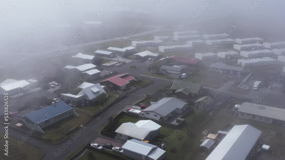 Residential buildings in Njardvik village with thick fog clouds, aerial ...