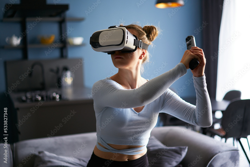 Young futuristic blonde girl wearing virtual reality headset, holding ...