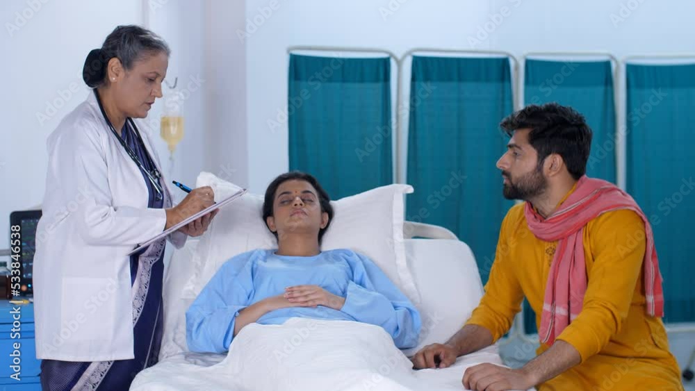 Middle-class Indian man with a beard sitting with a female patient in ...