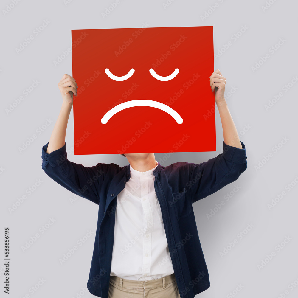 Man cover face using red paper with sad emoticon at gray background ...
