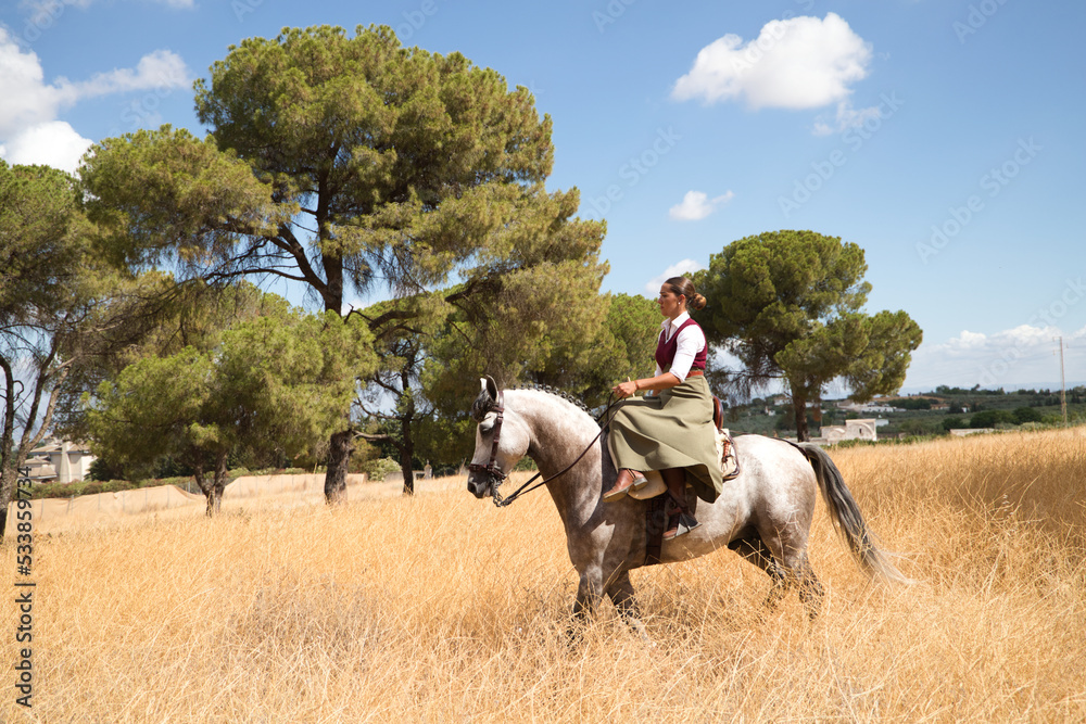 Young and beautiful Spanish woman on a Thoroughbred horse riding in the ...