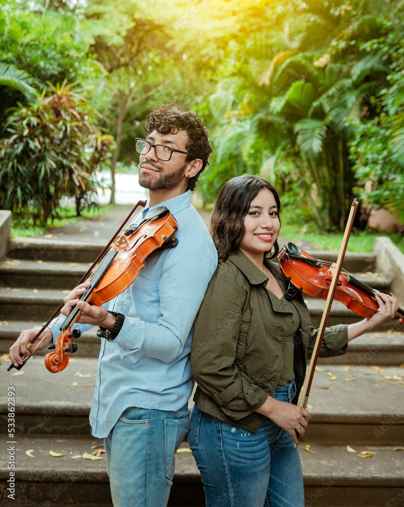 Portrait of two young violists back to back outdoors. Portrait of ...