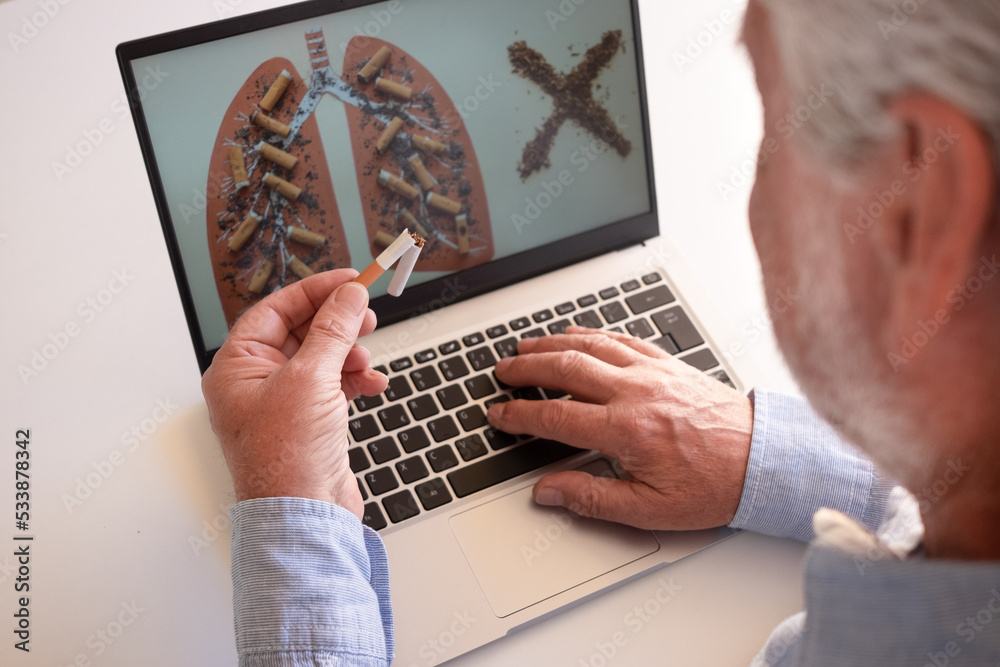 Adult man holding a broken cigarette over laptop keyboard, ready stop ...