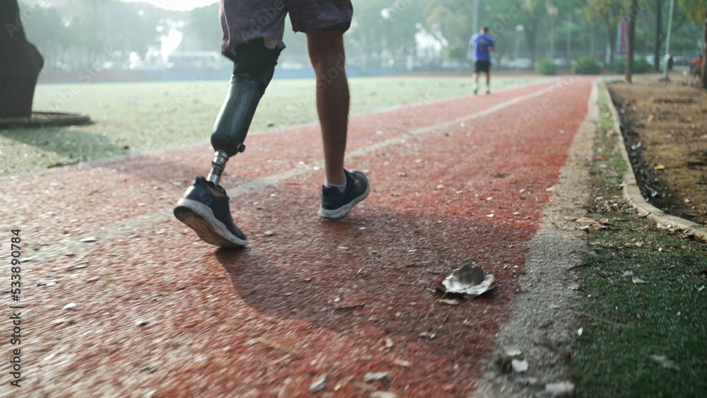 Determined disabled athlete running outside with prosthetic leg ...