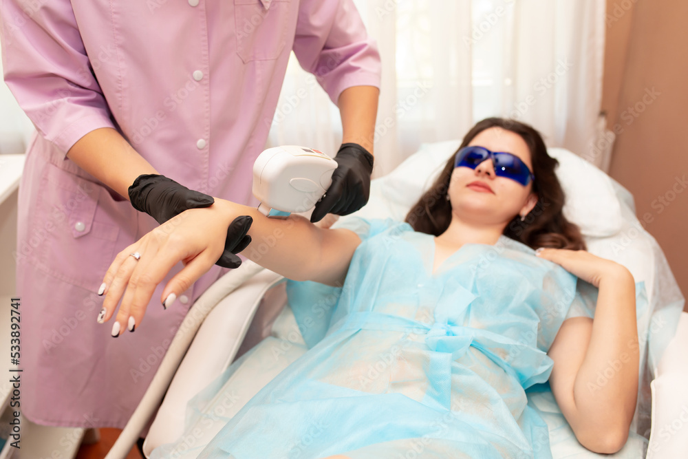 Laser hair removal procedure in a beauty salon. Master cosmetologist ...