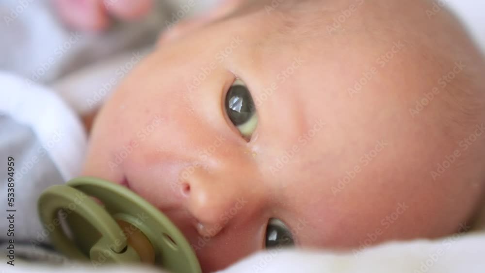newborn with pacifier. baby close-up with a pacifier lies in bed at ...