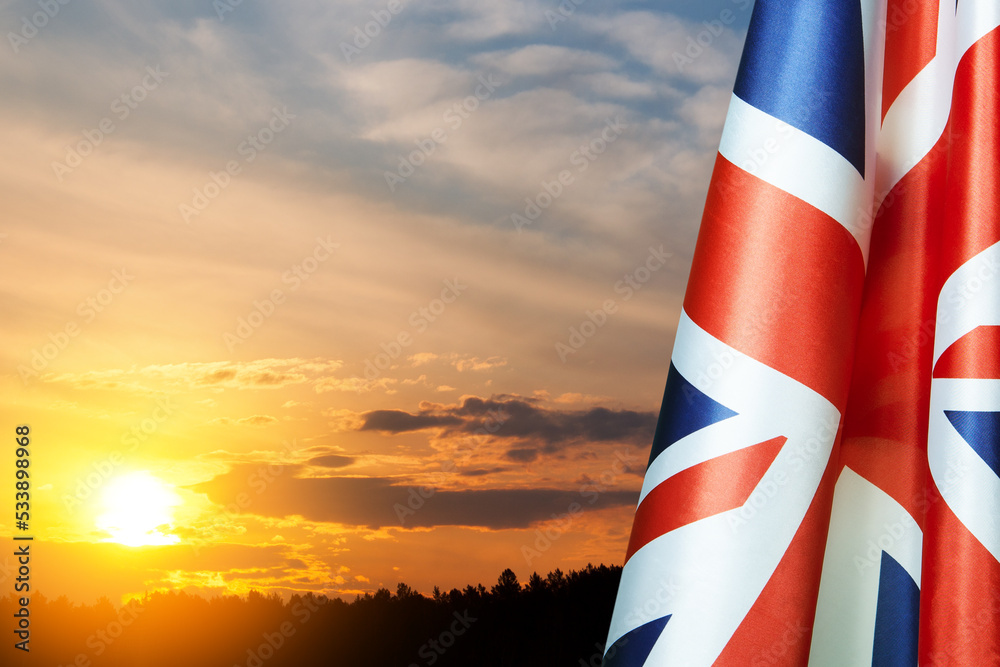 National flags of United Kingdom on a flagpole on sunset sky background ...