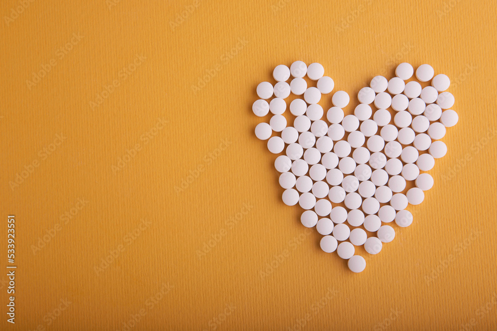 Heart shaped pills on a orange background. Medicines that help people ...
