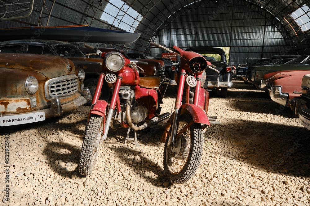 Two red retro vintage rusty old motorcycles are on exhibit in barn next ...
