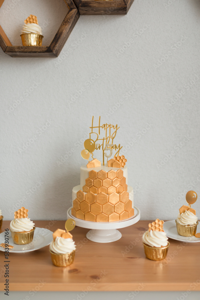 Making a sweet table for a birthday. Cake with honeycombs, golden ...