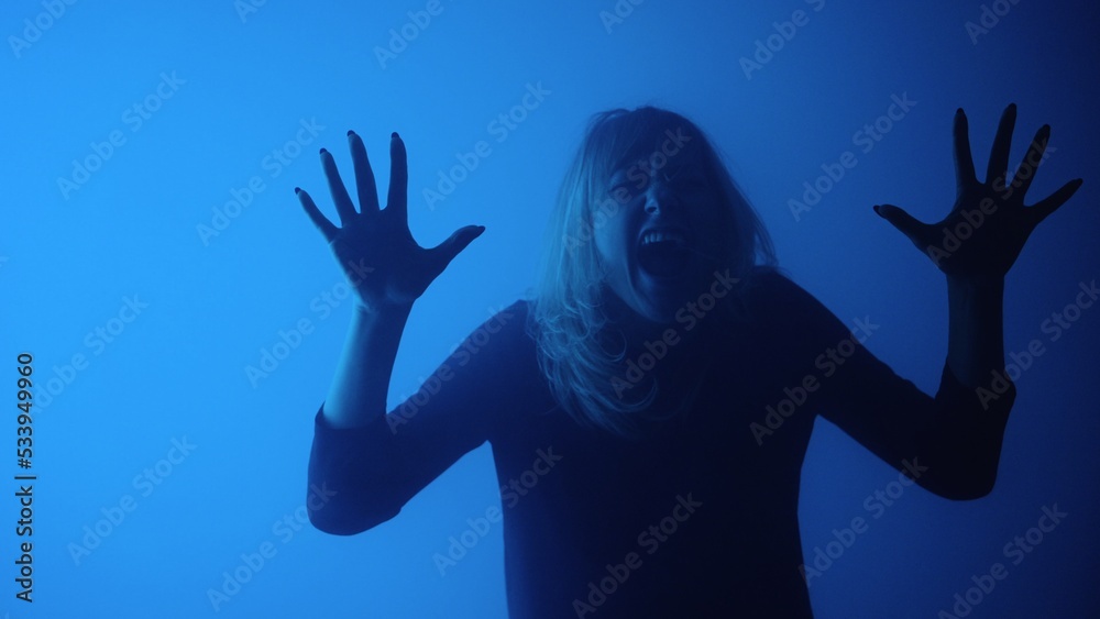 Woman touches glass with palms and and screams in fear and horror ...