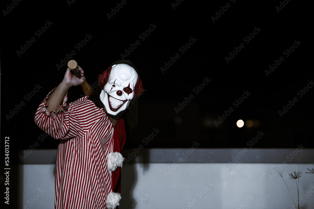 Asian handsome man wear clown mask with weapon at the night scene ...