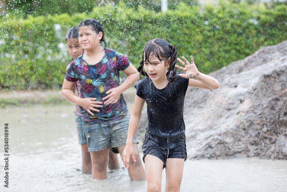 Group of happy children girl playing in wet mud puddle during raining ...