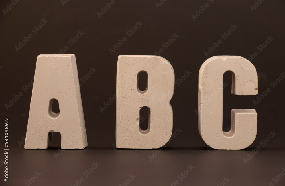 Volumetric letters A B C made of concrete on a black background ...