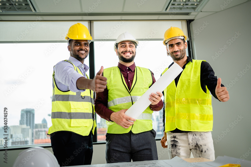 A team of happy engineers diverse shows thumbs up together looking at ...