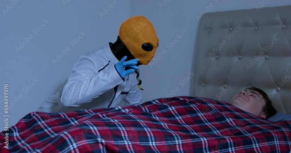 Man is sleeping in bed, alien with worm, larva in his hand leans over ...