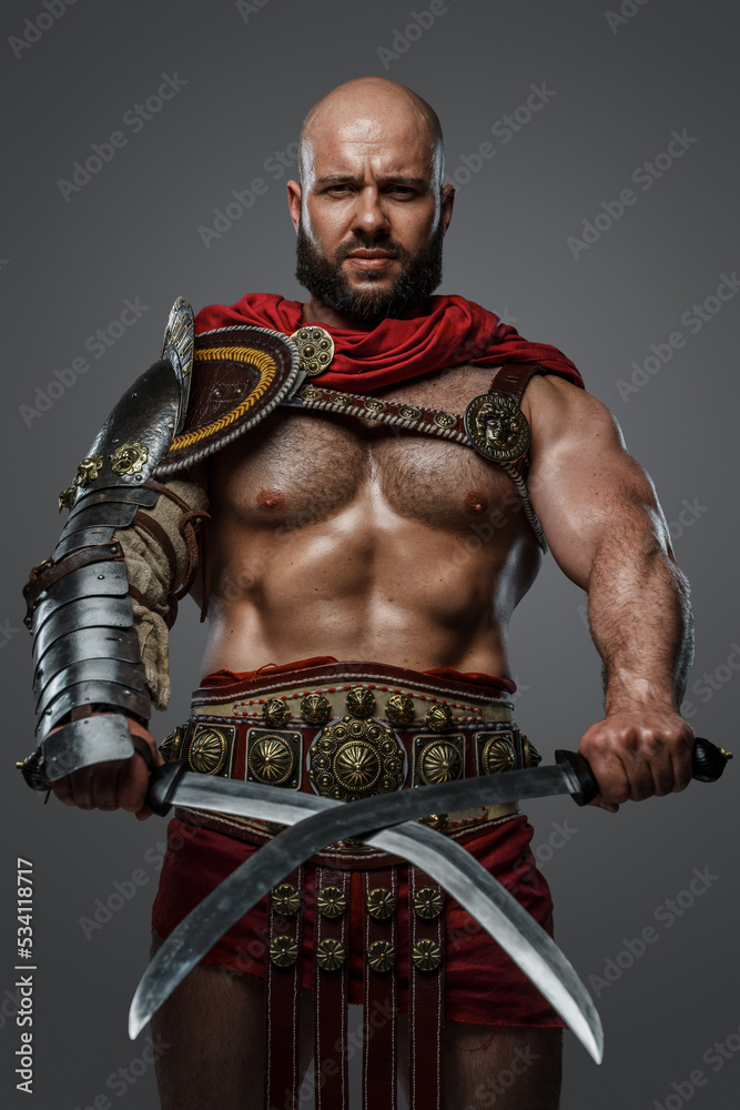 Portrait of ancient gladiator with bare torso posing with dual swords ...