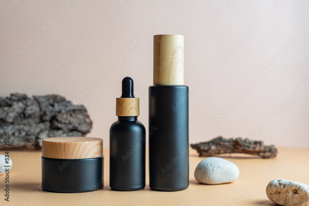 Set of natural cosmetics in black matte glass package on beige ...