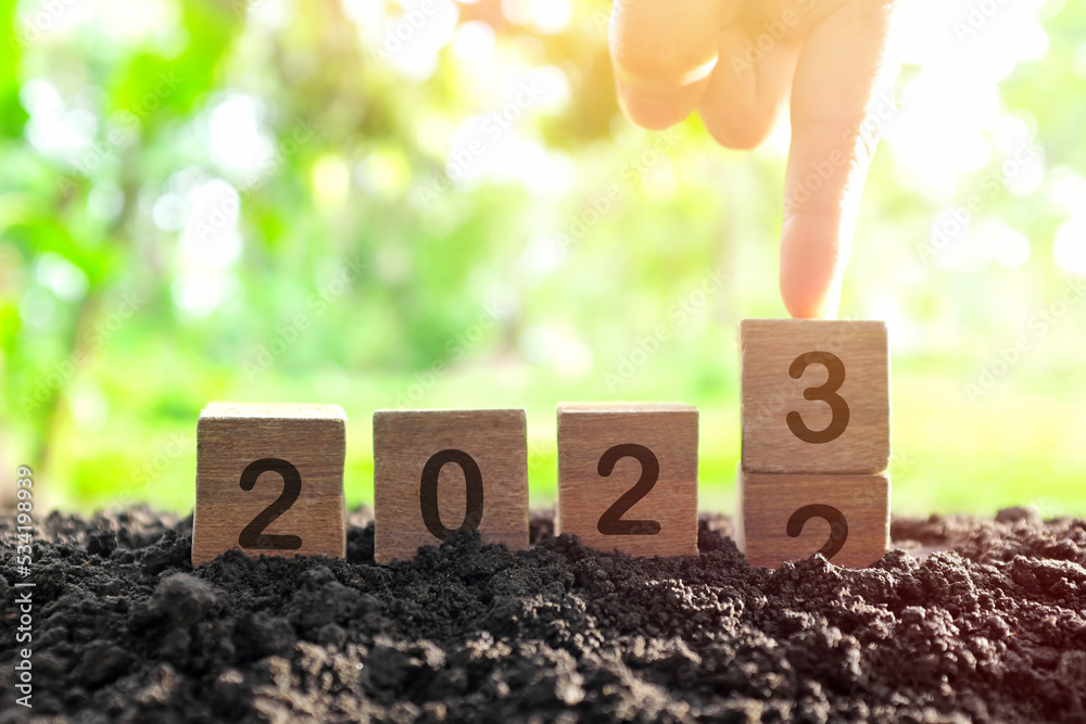 Hand changing year 2022 to 2023 in wooden blocks cubes with growing ...