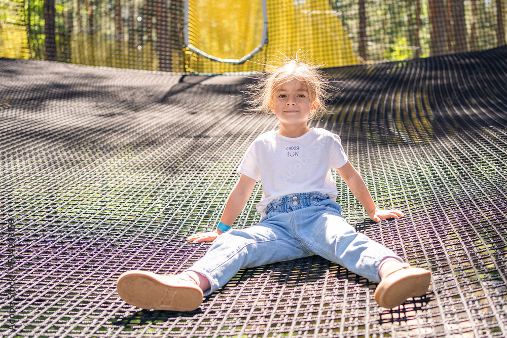 little girl having fun in adventure netting park. Child on tree top net ...