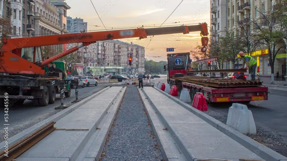 Orange construction telescopic mobile crane unloading tram rails from ...
