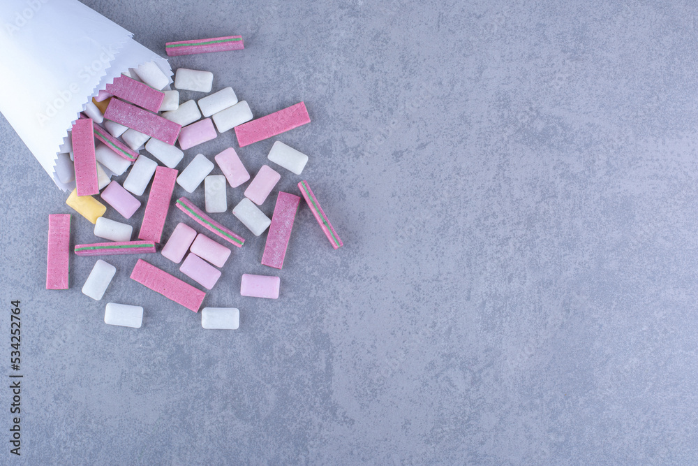 Strips and tablets of chewing gum pouring out of a paper wrapping on ...