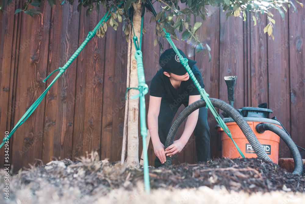 Preteen boy helps suction water with a shop vac to help prevent root ...