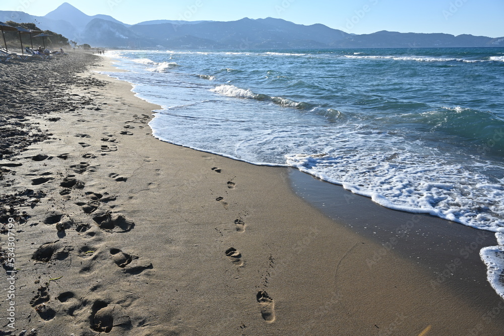 Sandy beach with footprints in the wet sand. Soft waves are washing ...