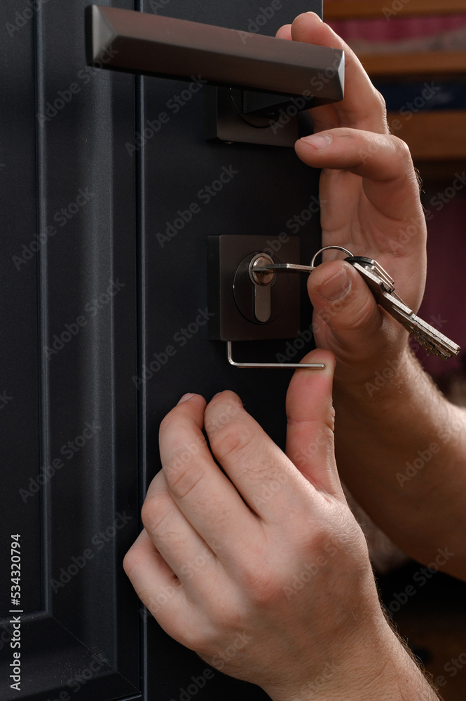 Installation of a door lock, a carpenter installs a door lock in a door ...