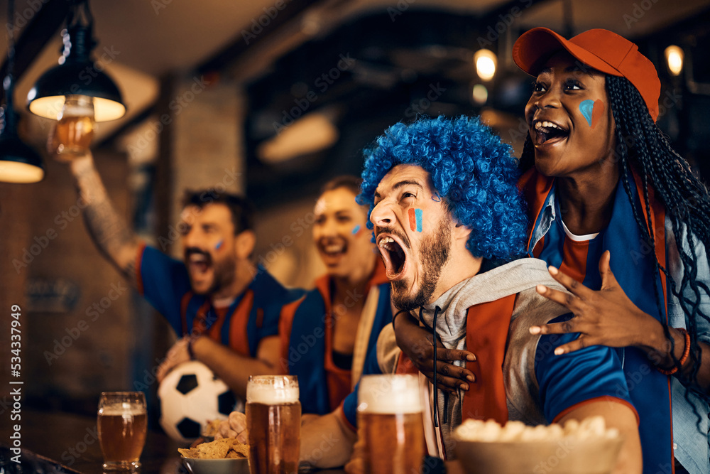 Passionate soccer fans scream while watching game on TV in pub. Stock ...