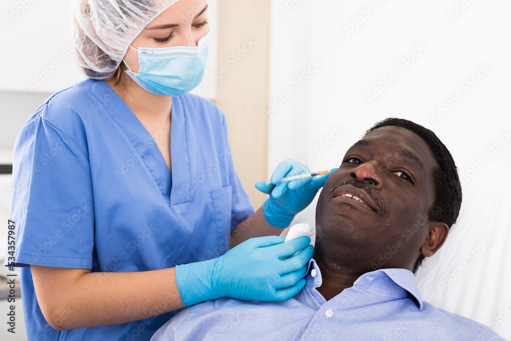 African american man getting injections for face skin tightening at ...