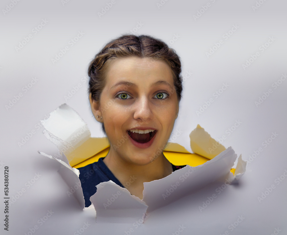 surprised young woman getting out from hole in paper breaking through ...