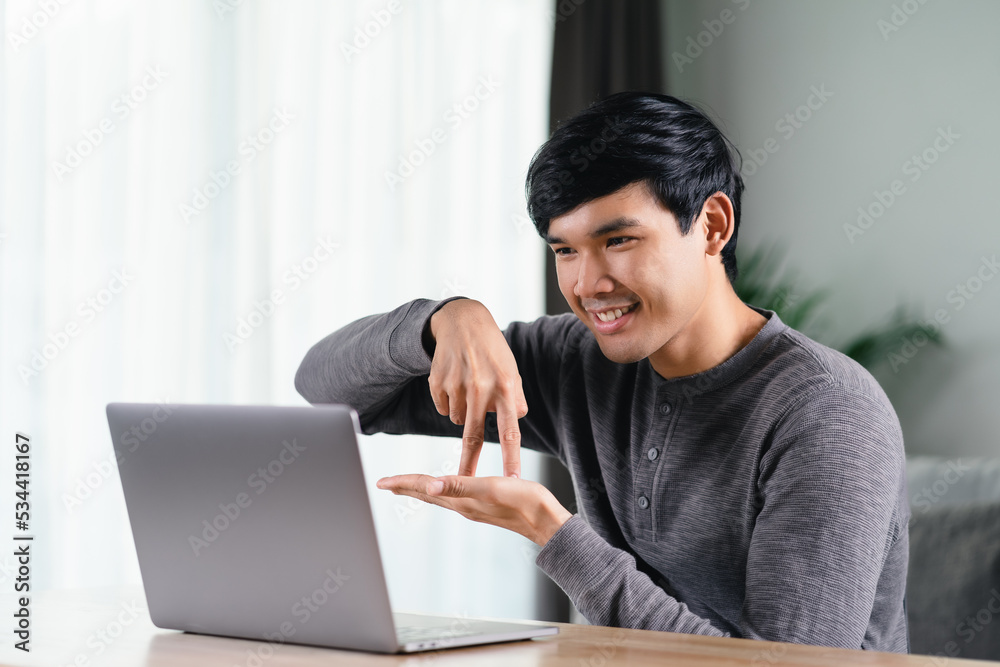 Foto de Young Asian man deaf disabled using laptop computer for online ...