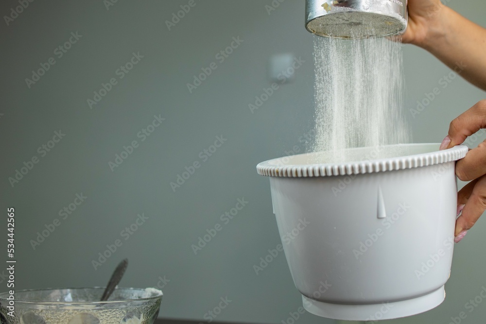 making cookies. sifting flour into a bowl. the flour expands and ...