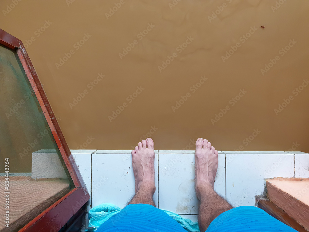 Bare feet at the front door of house overlooking brown muddy water ...