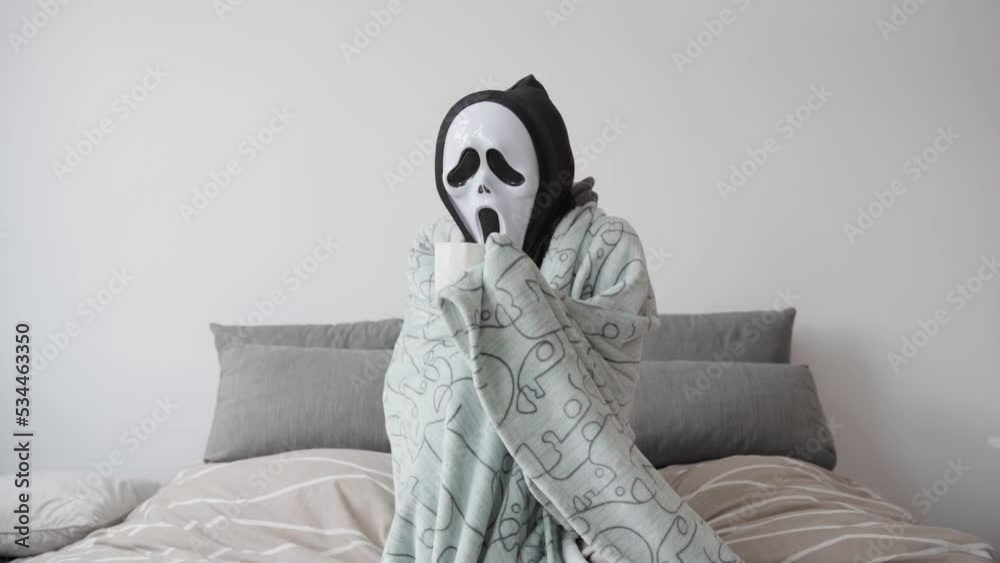 Unrecognised person in ghost sad mask in plaid freezing at home. Cold ...