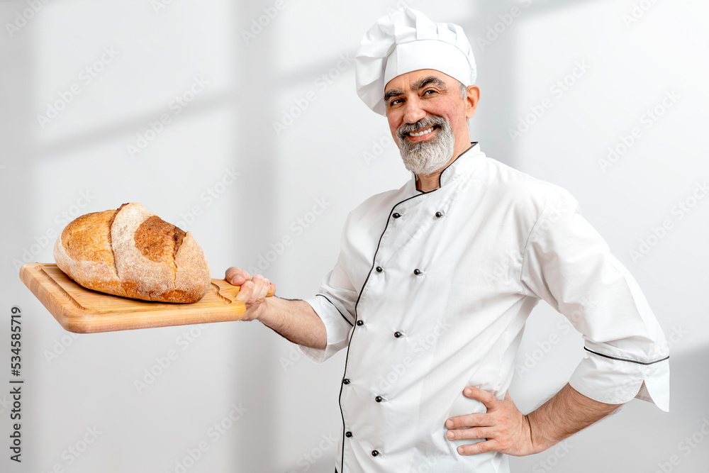Chef-cooker in chef's hat and jacket working in bakery, holding French ...