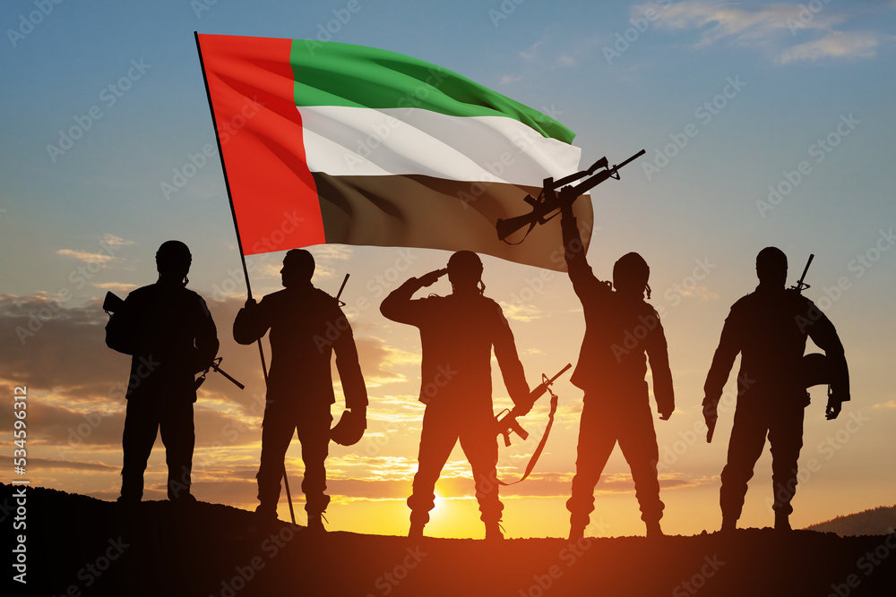 Silhouettes of soldiers with the flag of UAE on background of the ...