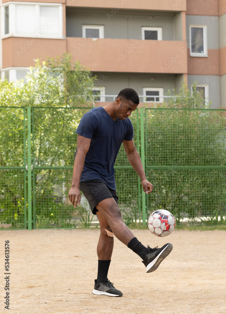 Young confident african american guy with taped knee kicks soccer ball ...