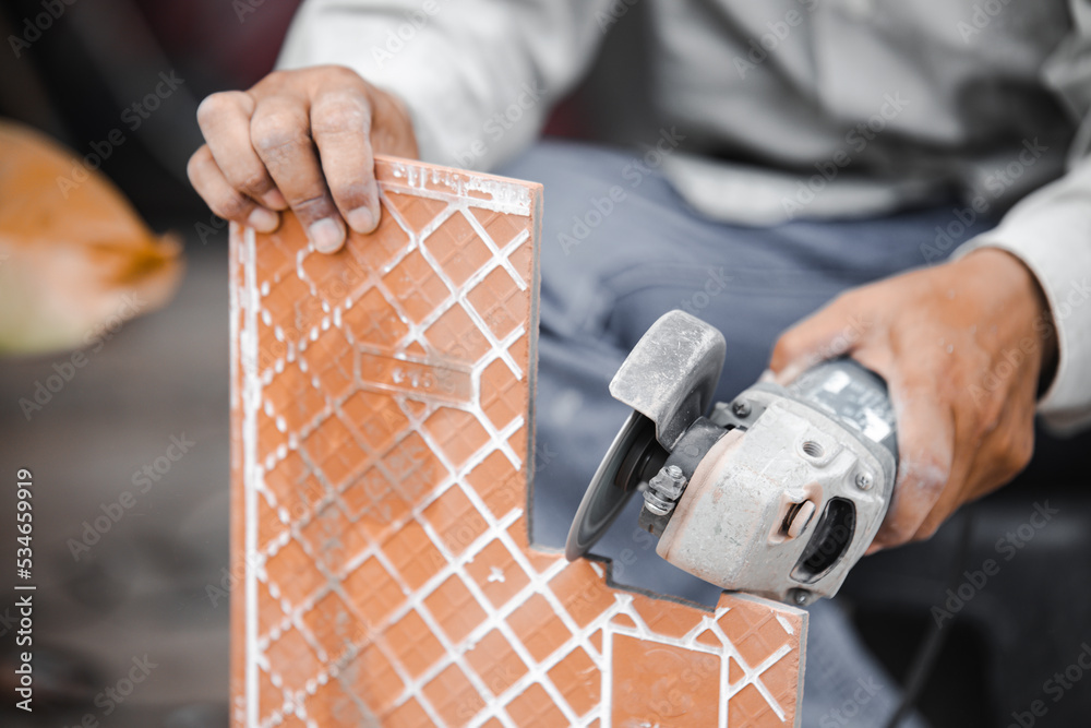 Worker cutting a tile using an angle grinder at construction site ...