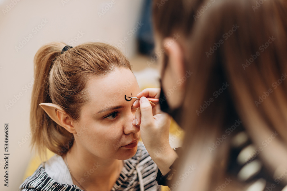 Make-up artist makes month moon on forehead face of young attractive ...