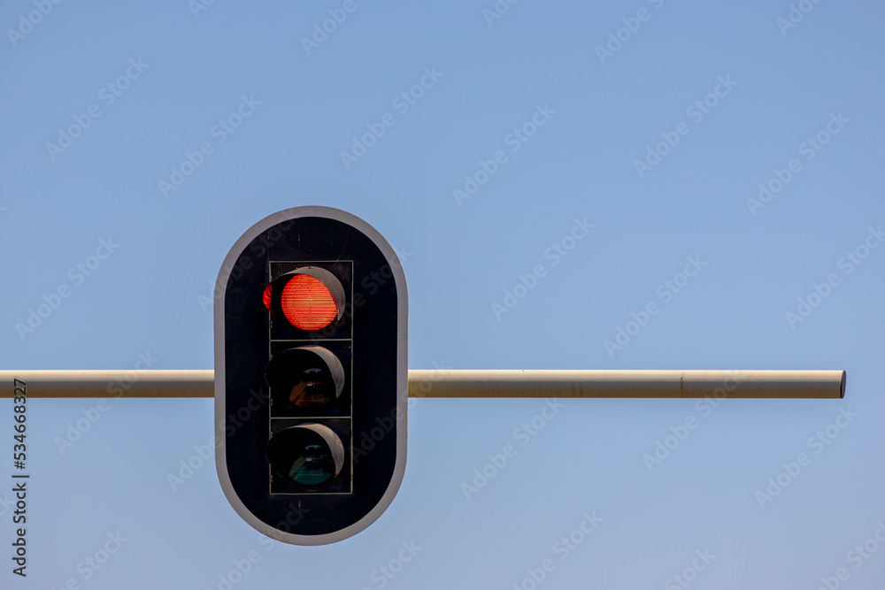 Traffic light hanging on the pole with blue clear sky as background ...