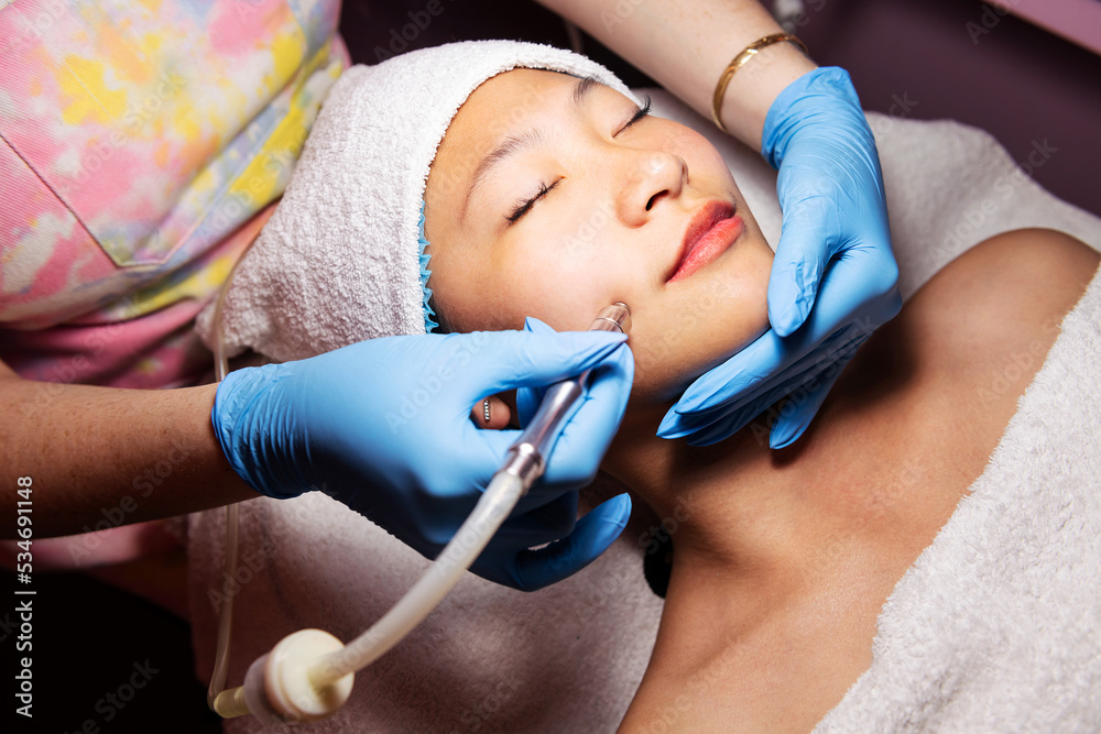 beautiful asian woman receiving a facial treatment with an exfoliating ...