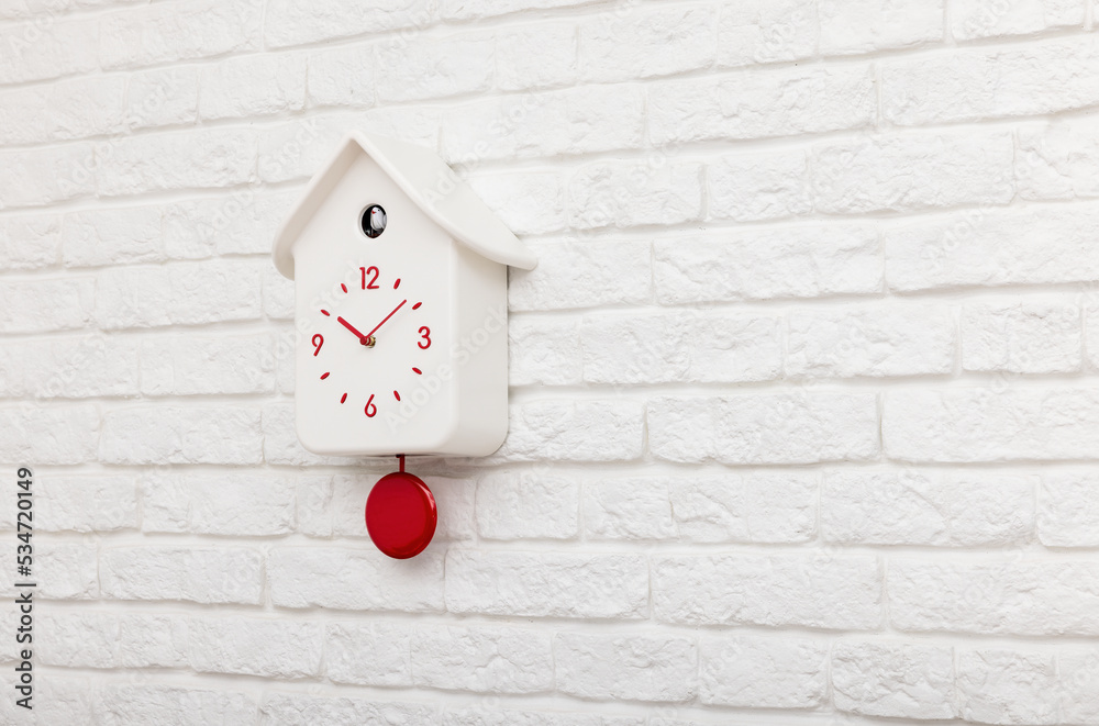 White cuckoo bird clock with red round pendulum and dial on a white ...