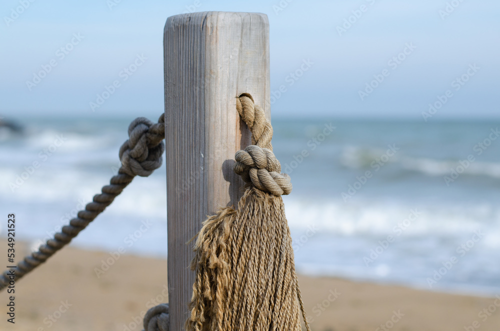 Wooden platform on the seashore. Fence made of old marine rope. Rope ...