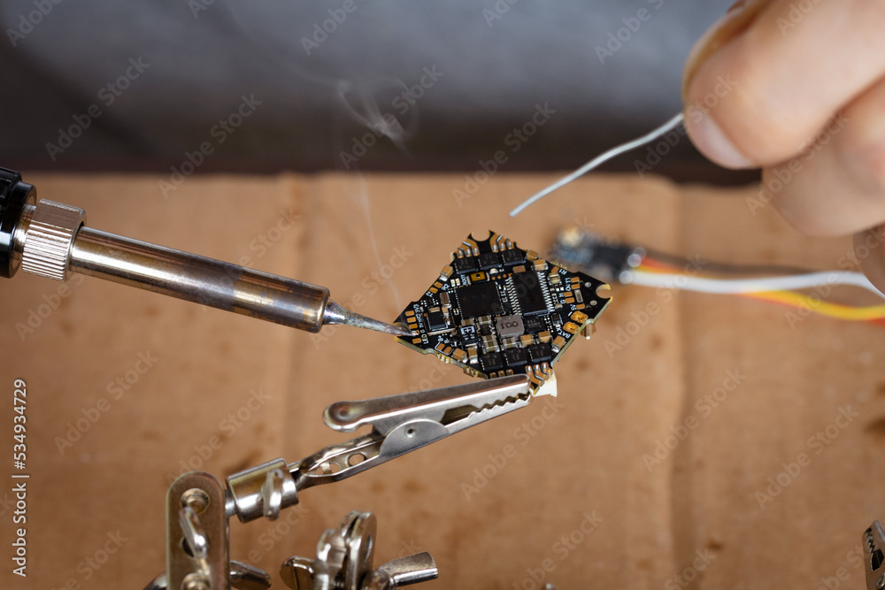 The hand holding the tin, a soldering iron solder the chip in place. a ...