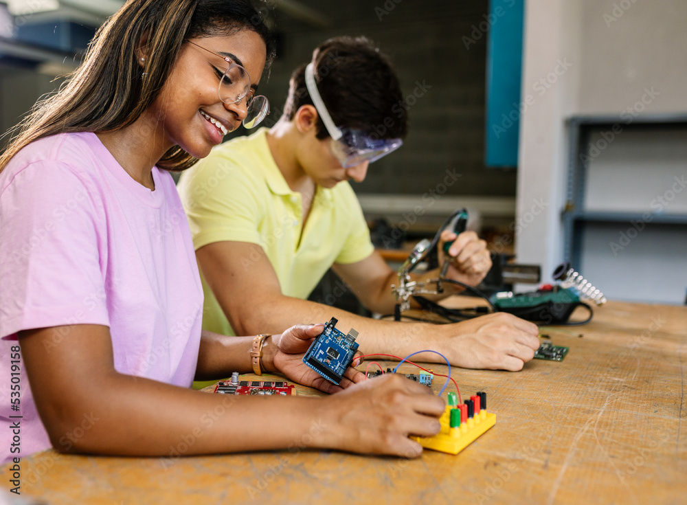 Young diverse students learning together at stem robotics class ...