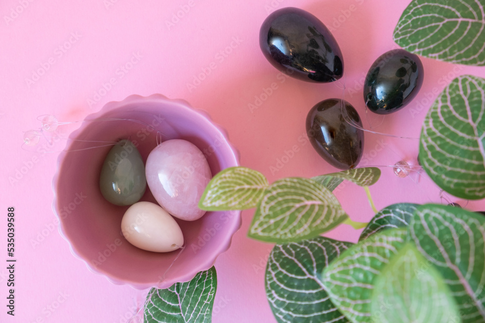 Colorful crystal yoni eggs laying in pink ceramic bowl on bright pink ...