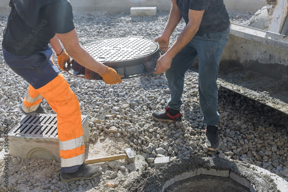 Cast iron sewer hatch being installed on concrete base as part of the ...