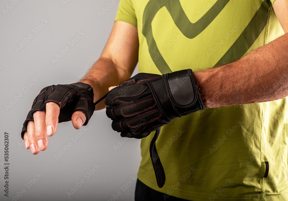 Wearing, putting on sport workout gloves close up for palm and wrist ...